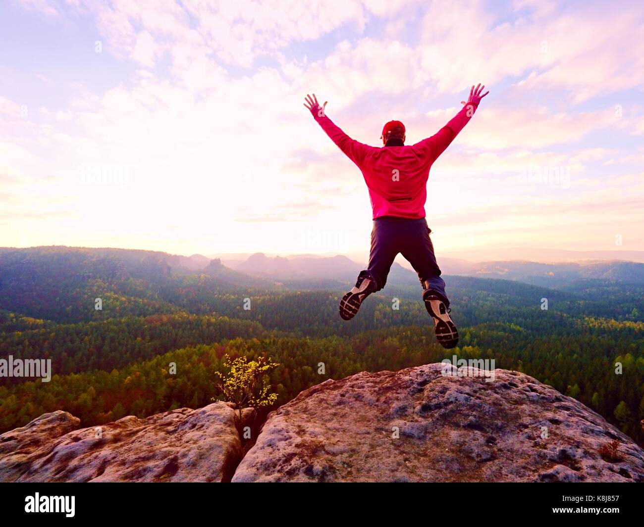 Crazy man. Hiker is jumping on the rocky peak. Wonderful mood in rocky ...