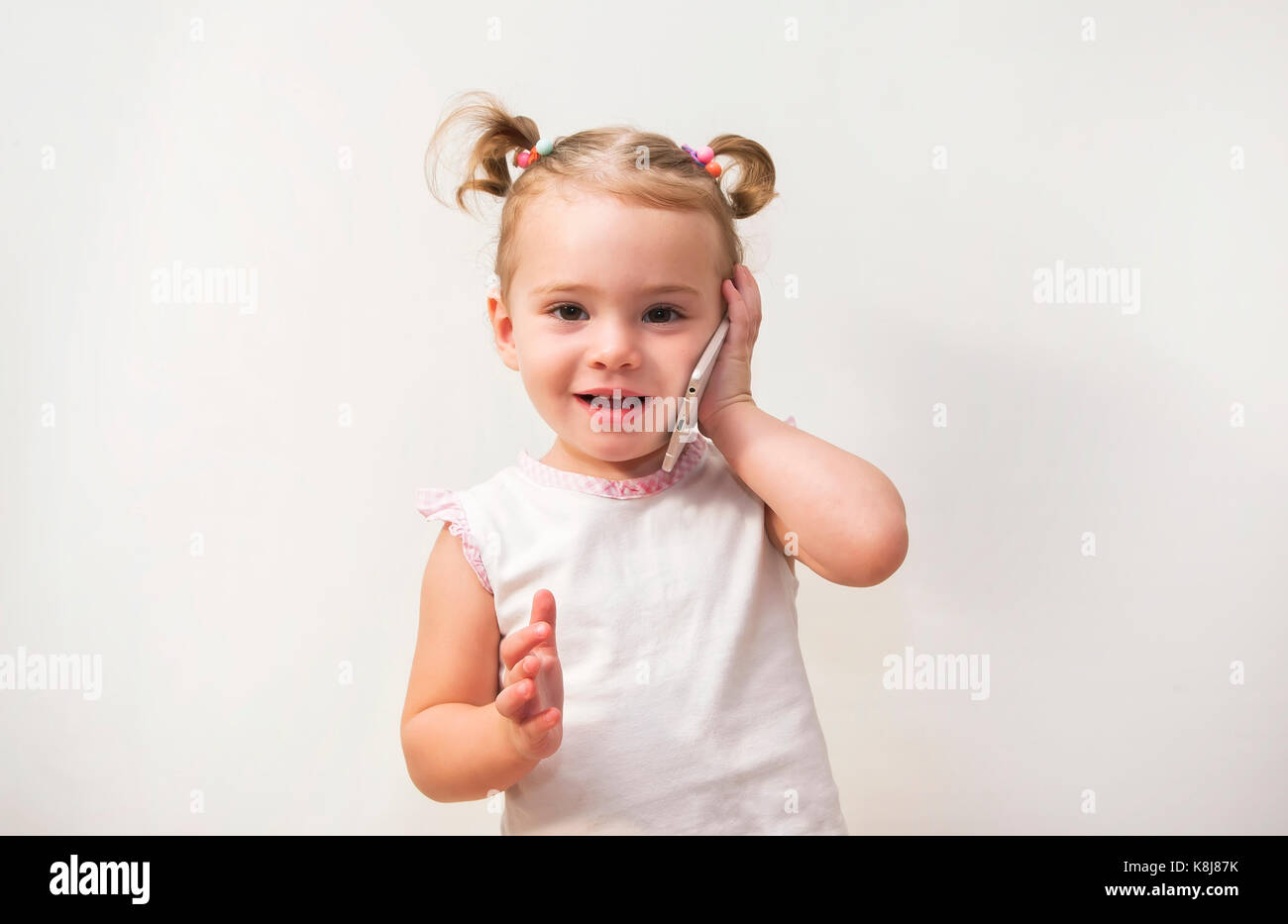 Little girl speaking by cell phone, white background Stock Photo - Alamy