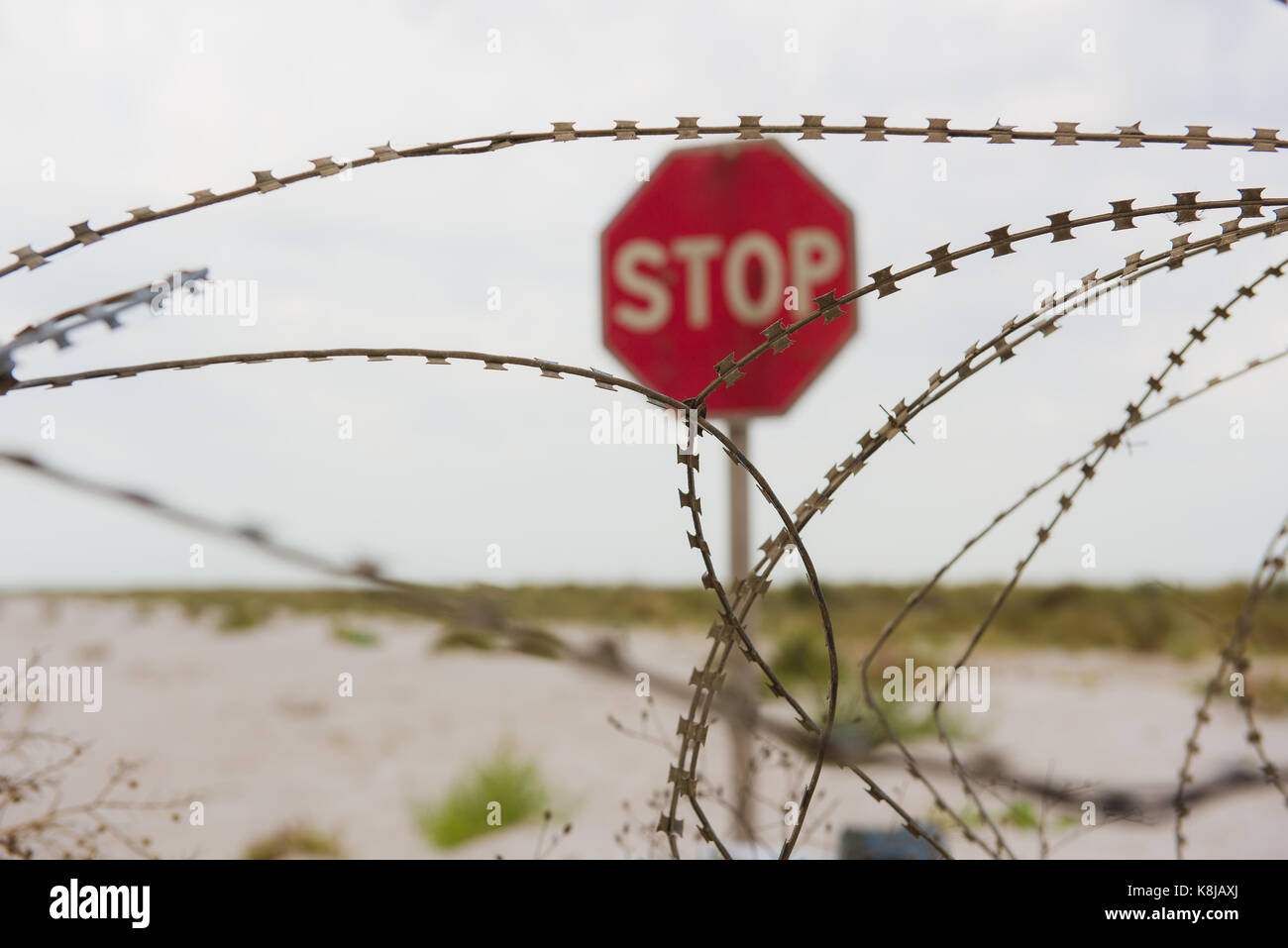 Red stop sign behind safety fence of barbed wire Stock Photo - Alamy