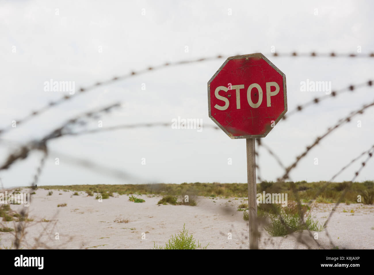 Red stop sign behind safety fence of barbed wire Stock Photo - Alamy