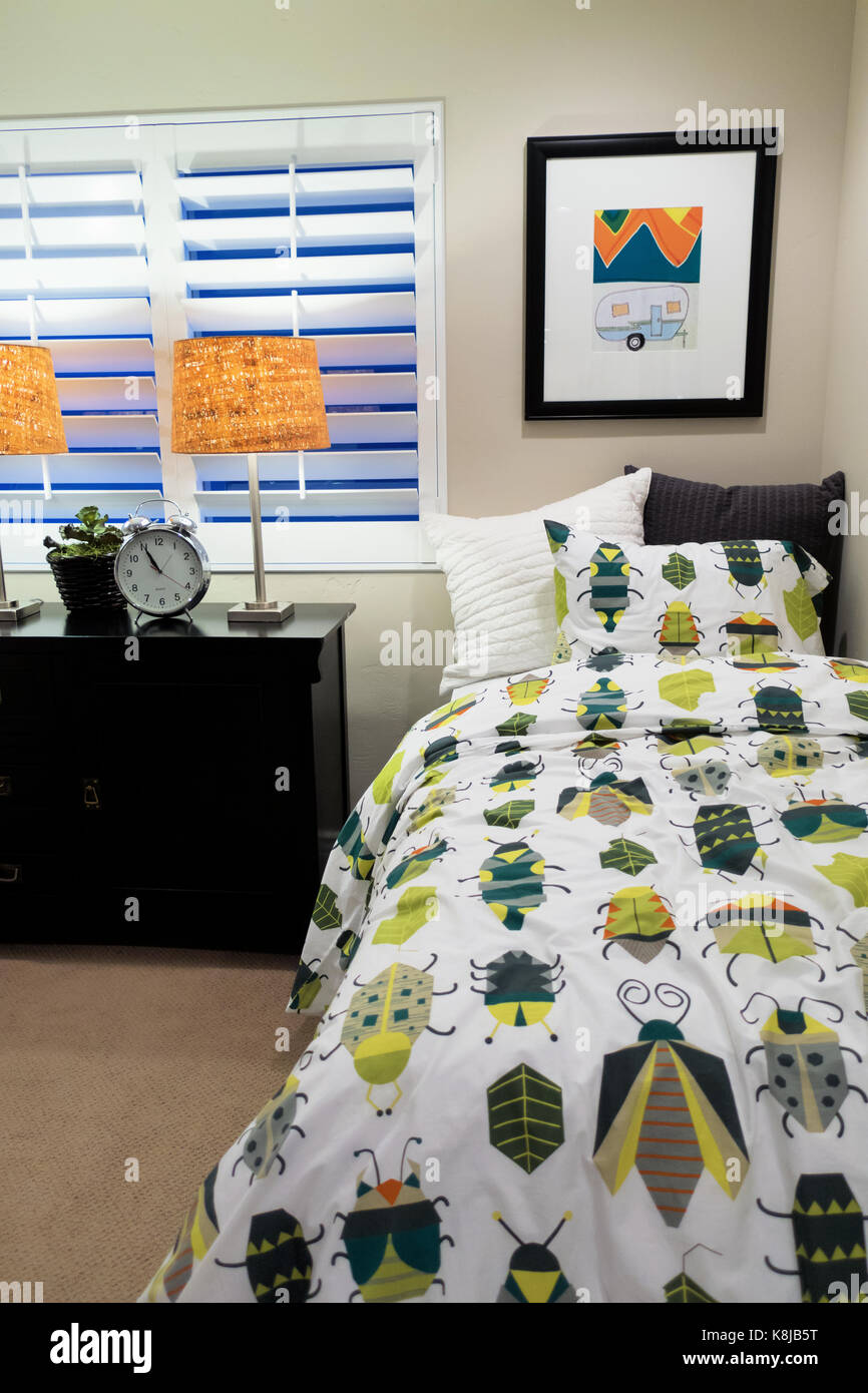 A double bed with a colorful bug comforter and a nightstand Stock Photo ...