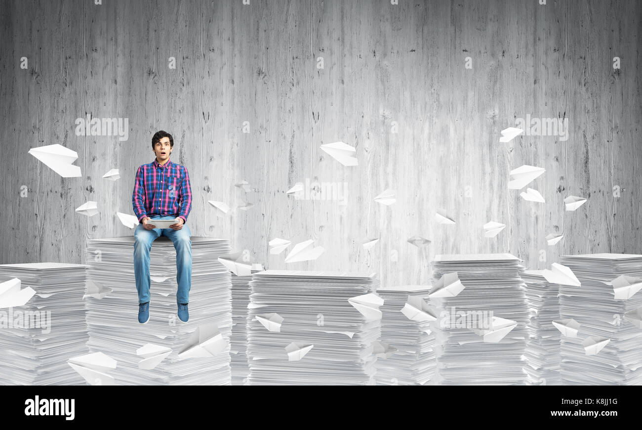 Attractive man sitting on pile of paper documents Stock Photo - Alamy