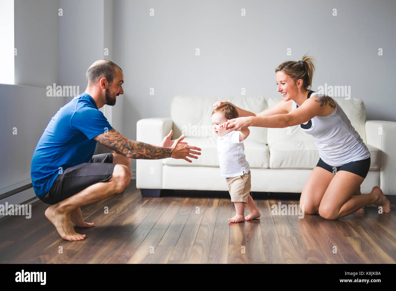 Cheerful mom and dad help their son to walk at home Stock Photo - Alamy
