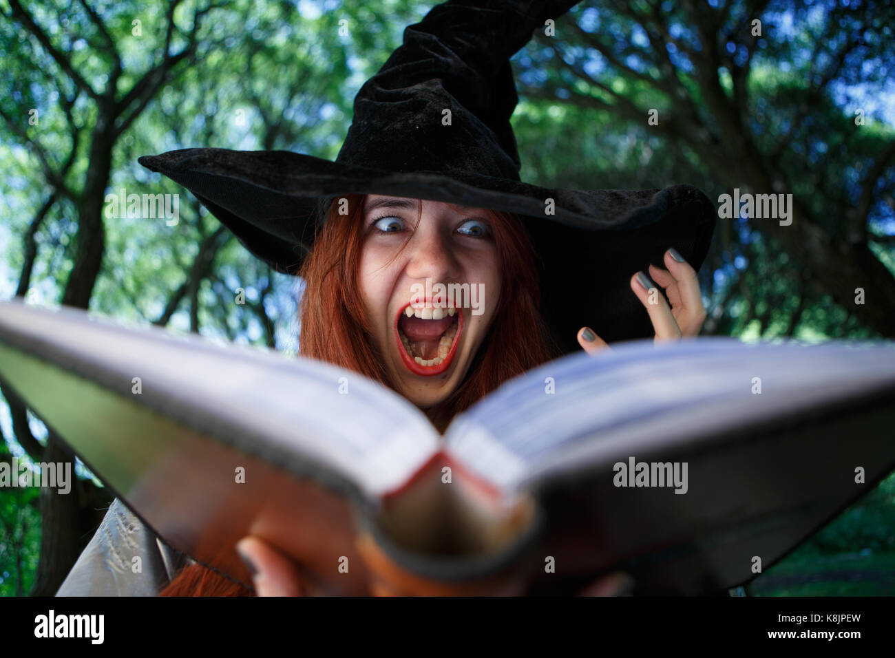 Portrait of witch with open magic book Stock Photo - Alamy