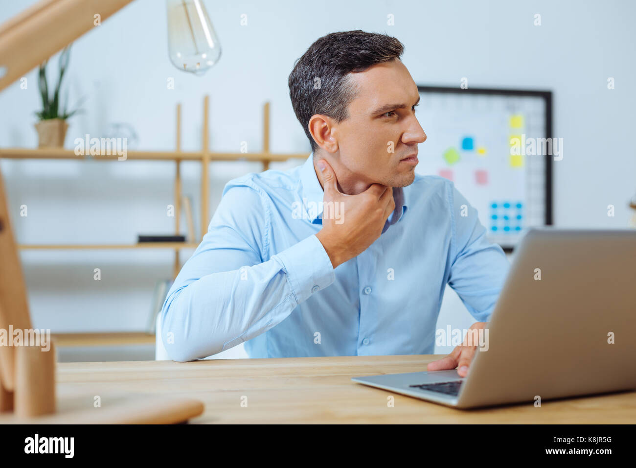 Serious male person touching his neck Stock Photo - Alamy