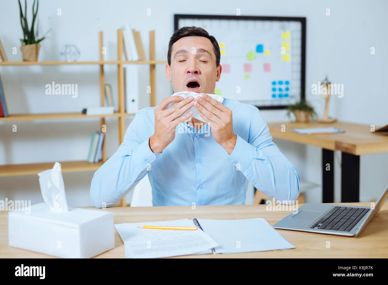 Ill office worker sneezing on camera Stock Photo - Alamy