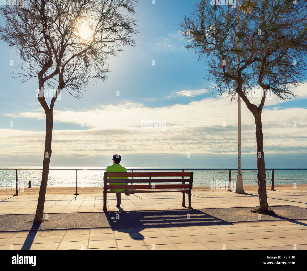 man tourist resting on a bench and looking at the beach Stock Photo - Alamy