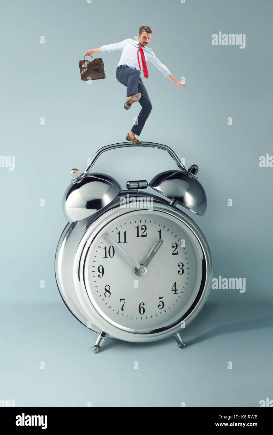 Businessman balancing over alarm clock Stock Photo - Alamy