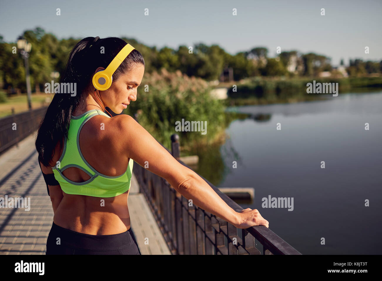 Spanish girl running in headphones at lake in park Stock Photo - Alamy