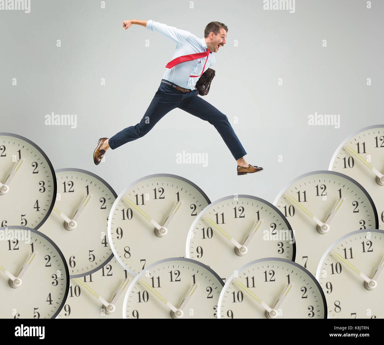 Businessman running over alarm clock Stock Photo - Alamy