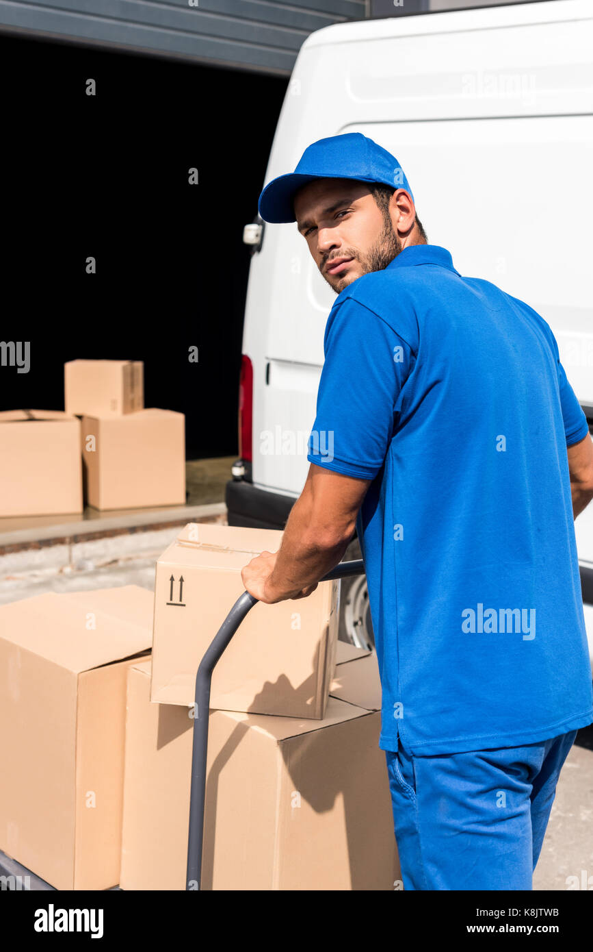 delivery man driving cart with boxes Stock Photo - Alamy