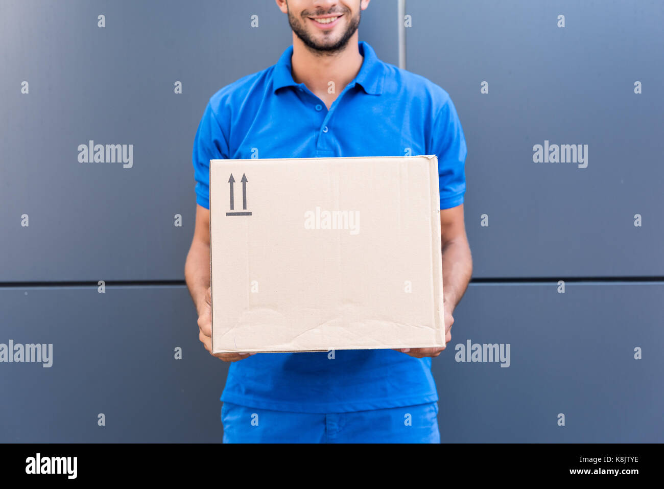 Delivery person delivering package smiling happy in blue uniform ...