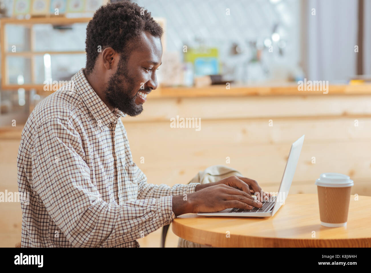 Happy young man typing on the laptop in cafe Stock Photo - Alamy