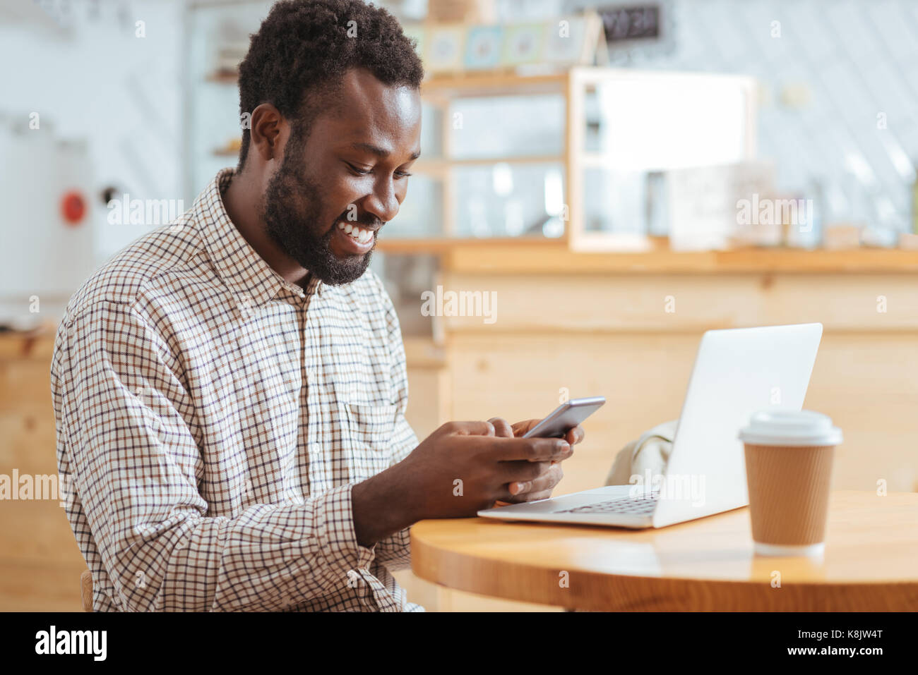Happy man reading message on phone while sitting in cafe Stock Photo ...