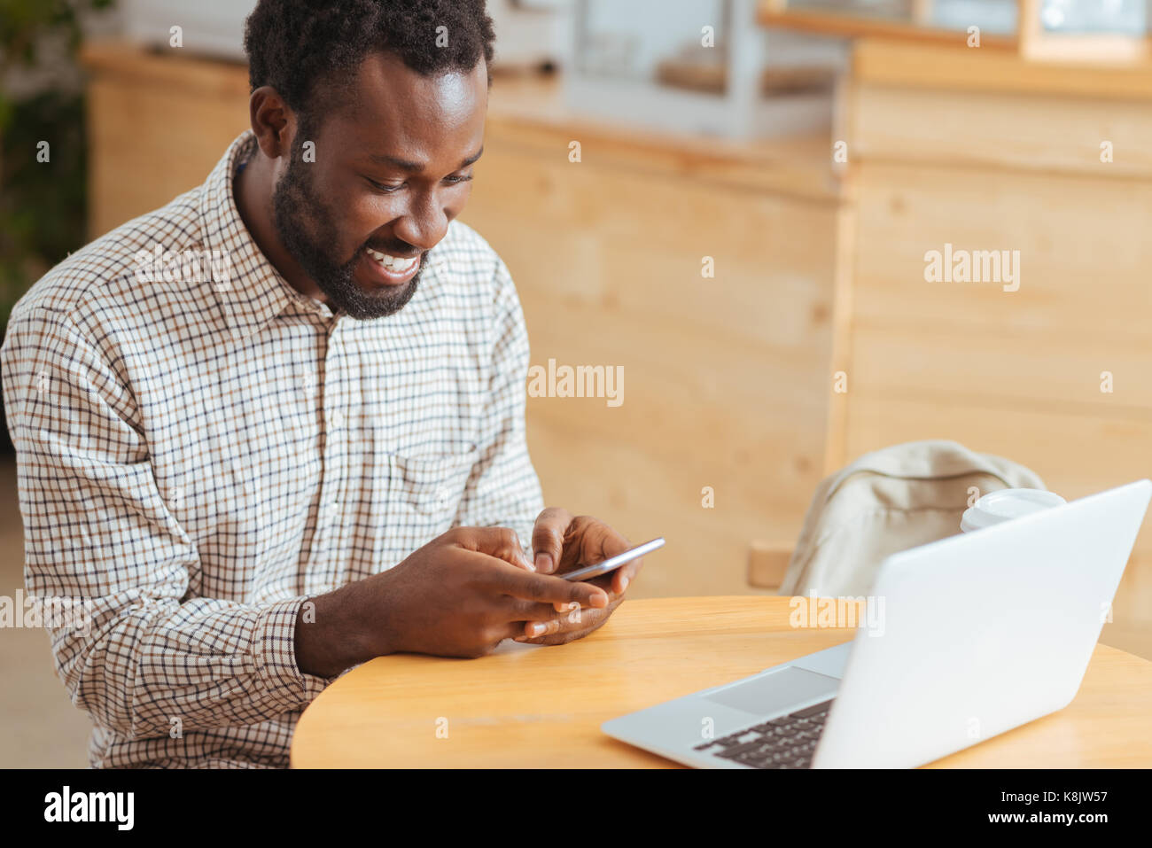 Happy young man texting friends in cafe Stock Photo - Alamy