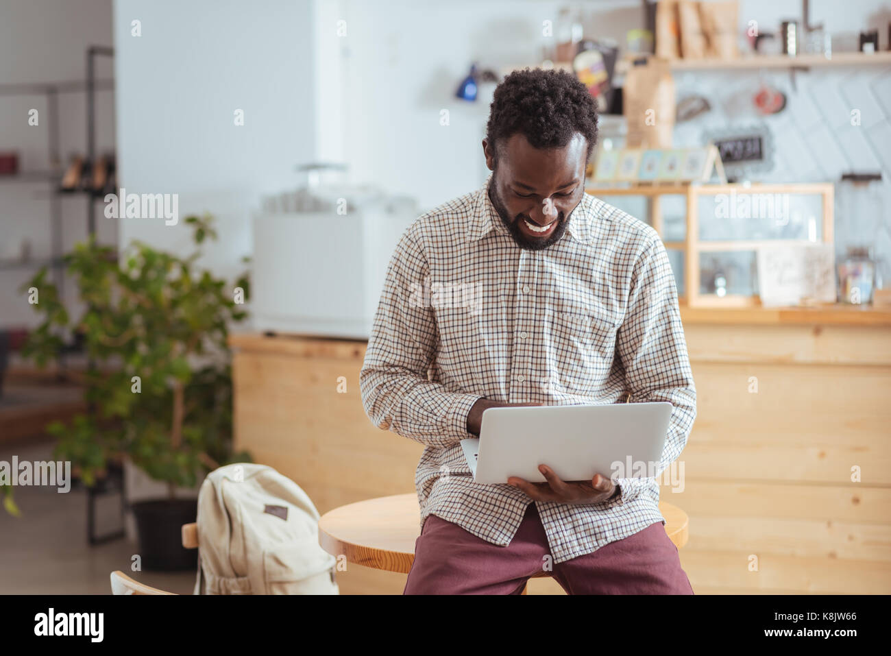 Cheerful man sitting on table and working on laptop Stock Photo - Alamy