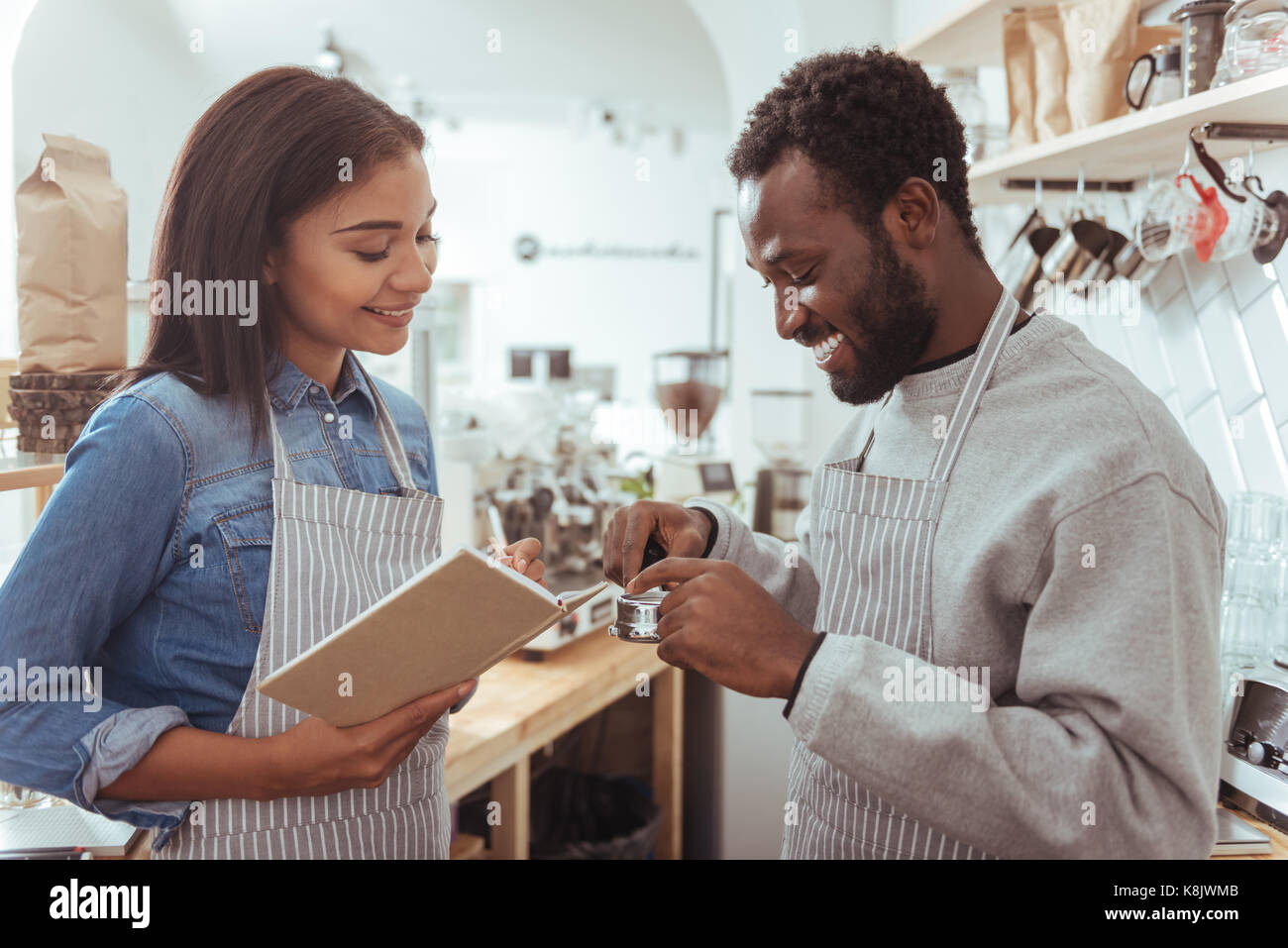 Female barista making notes while her colleague scrutinizing ...