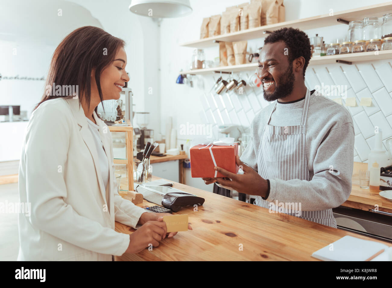 Smiling barista giving his customer a box with order Stock Photo - Alamy