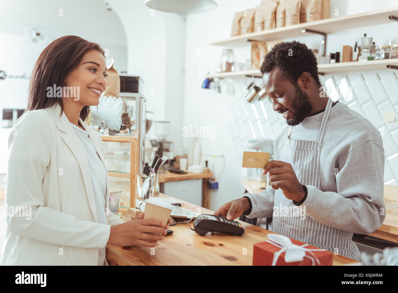 Smiling barista carrying out payment procedure Stock Photo - Alamy