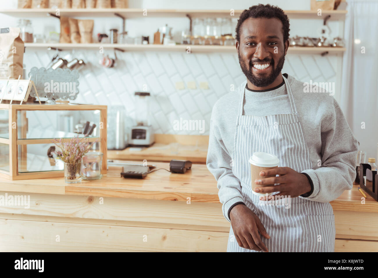 Smiling barista posing with a cup of coffee Stock Photo - Alamy