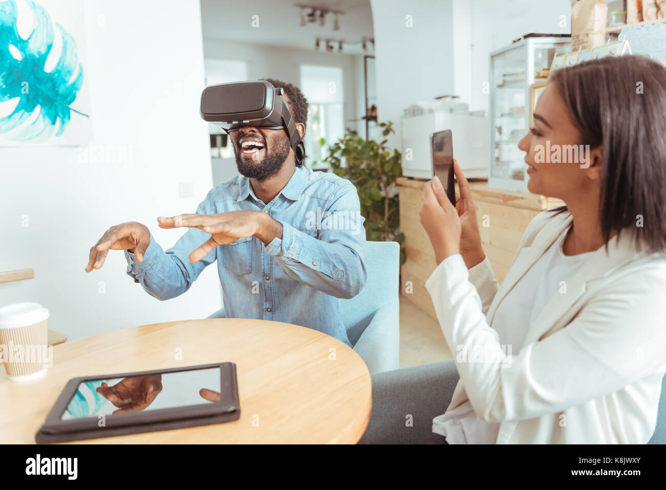 Joyful woman filming her friend test VR headset Stock Photo - Alamy