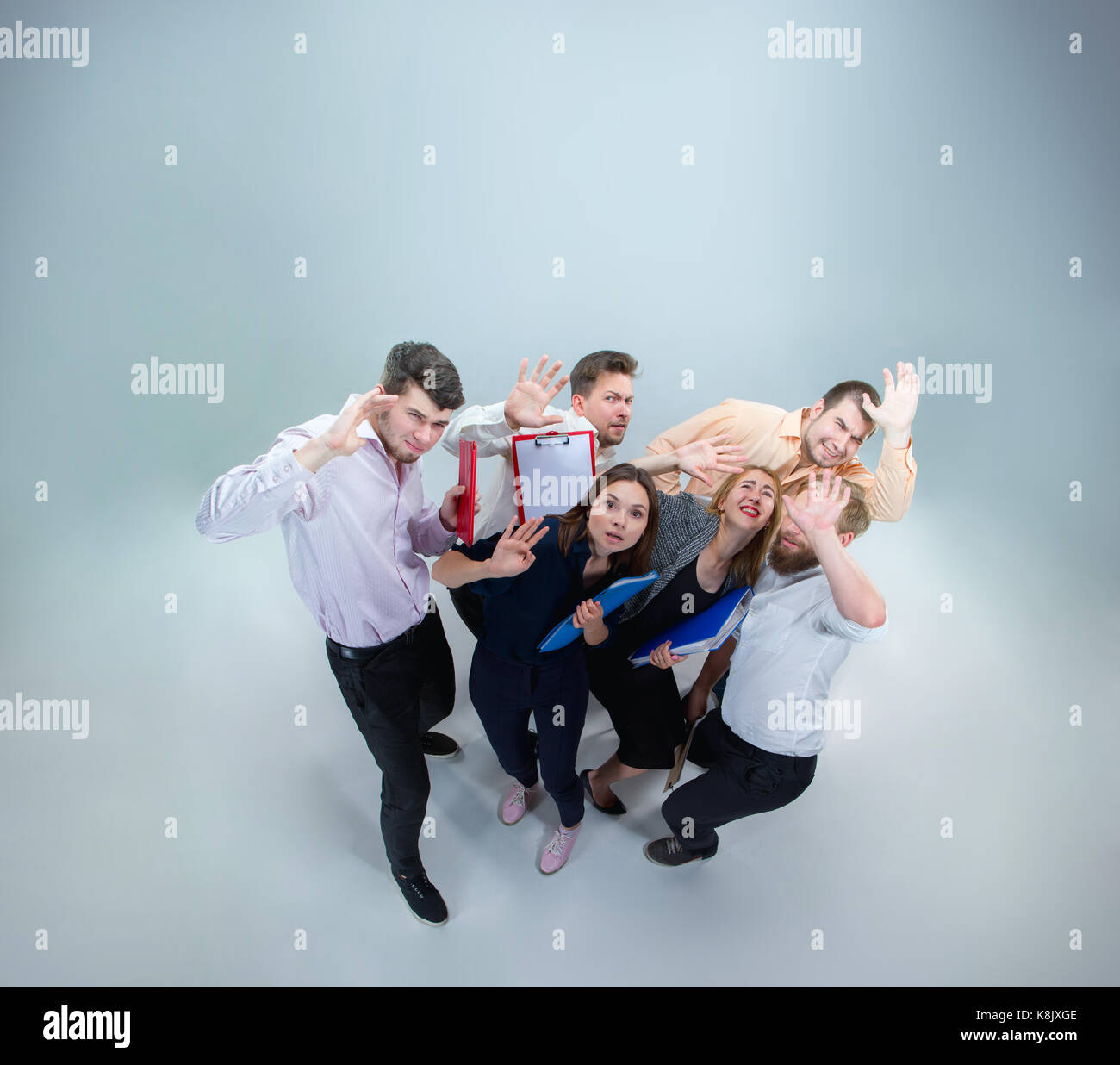 Scared and shocked team of young business men and women under boss ...