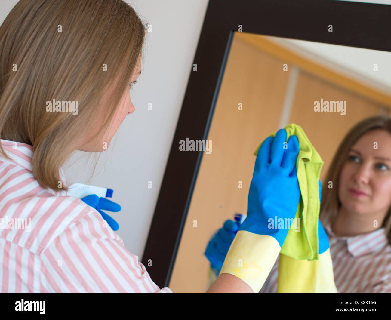 House cleaning. Woman is wiping mirror in the room Stock Photo - Alamy