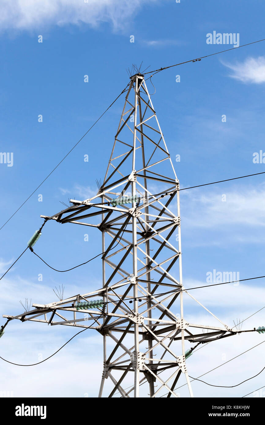 High-voltage power lines installed on metal posts on the blue sky ...