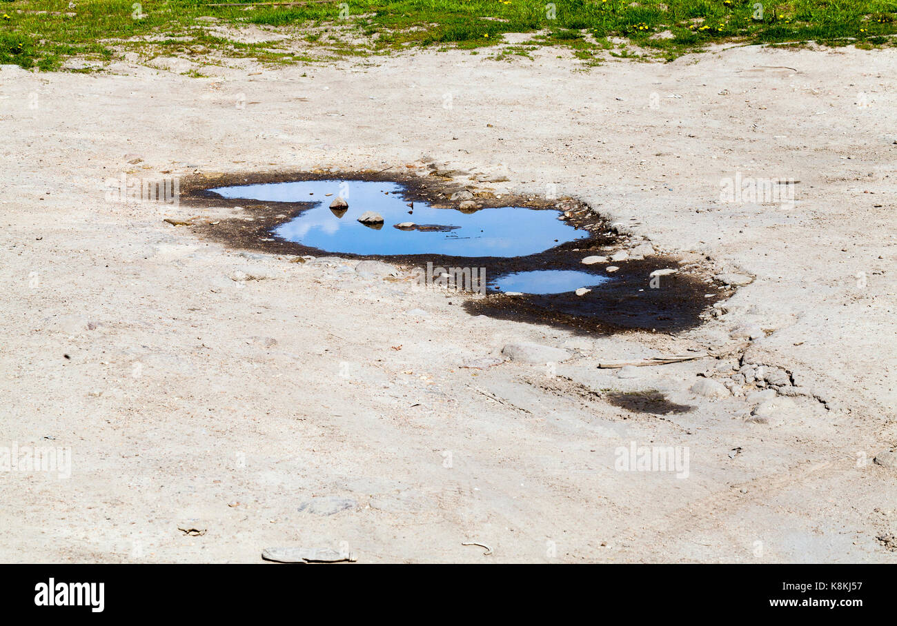 Dirty puddle in a hole on a rural road. Photo close up Stock Photo - Alamy