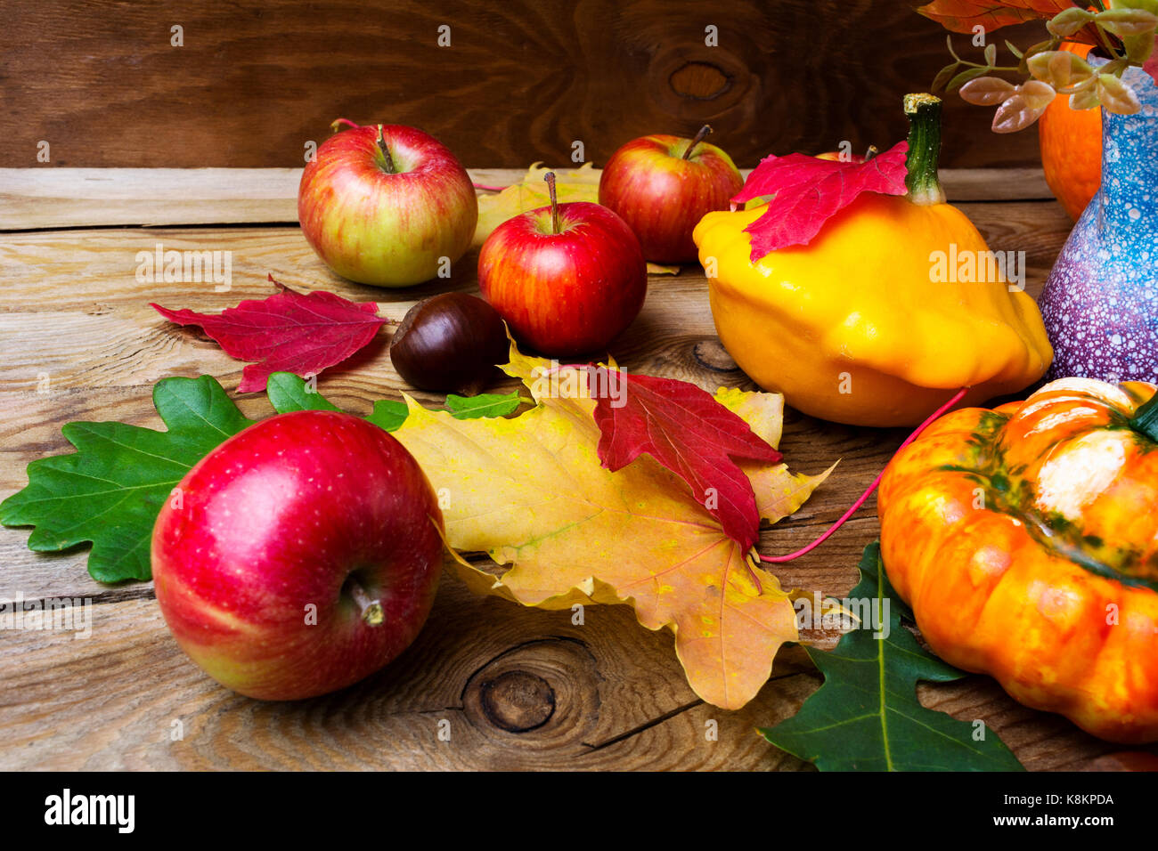 Ripe red apples and yellow gourd with colorful autumn leaves, close up ...