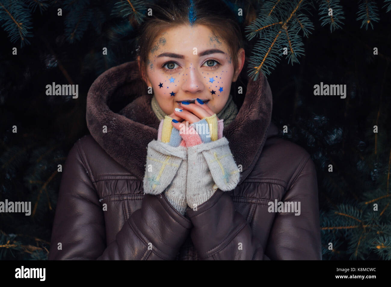 Winter portrait of a girl with bright make up and blue stars on face ...