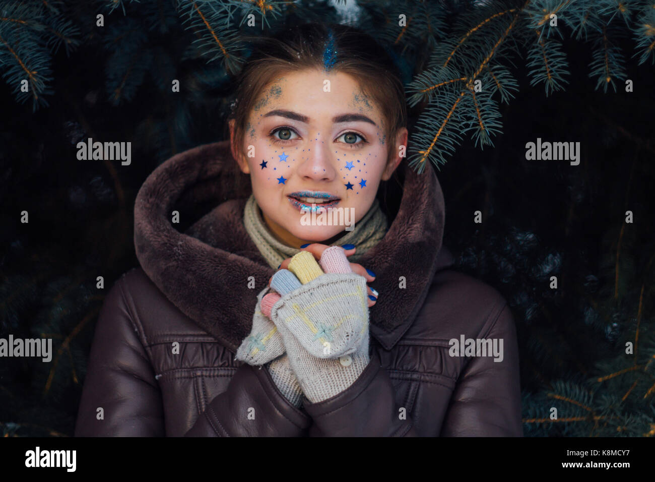 Winter portrait of a girl with bright make up and blue stars on face ...