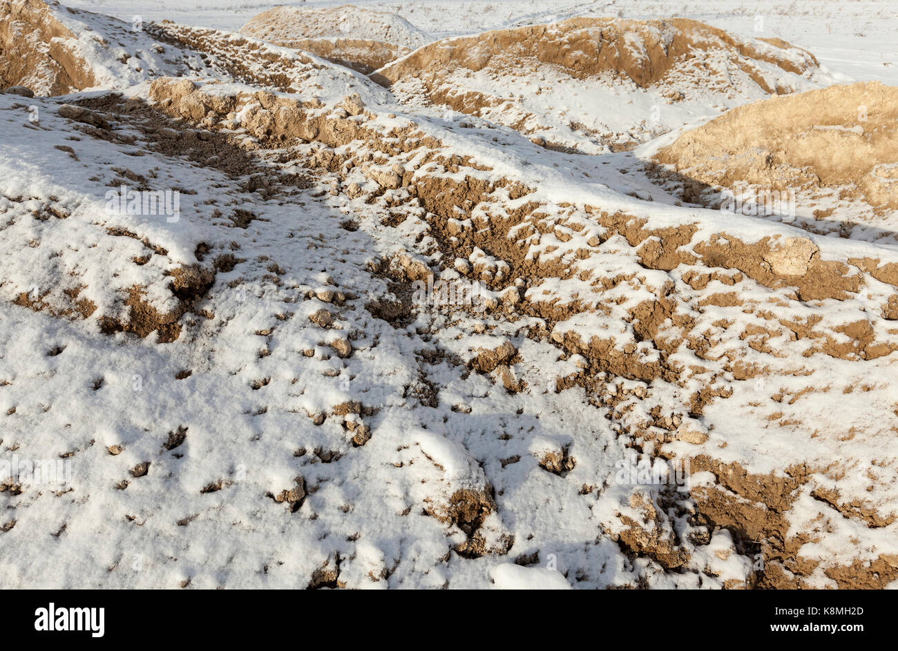 close-up photograph of several piles of sand covered with snow after a ...