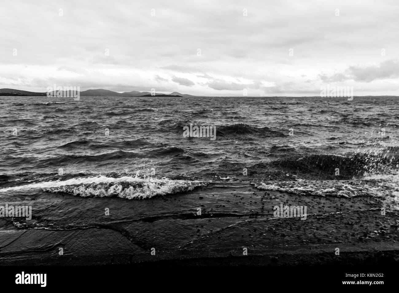 Water waves splashing on a pavement on a lake shore Stock Photo - Alamy