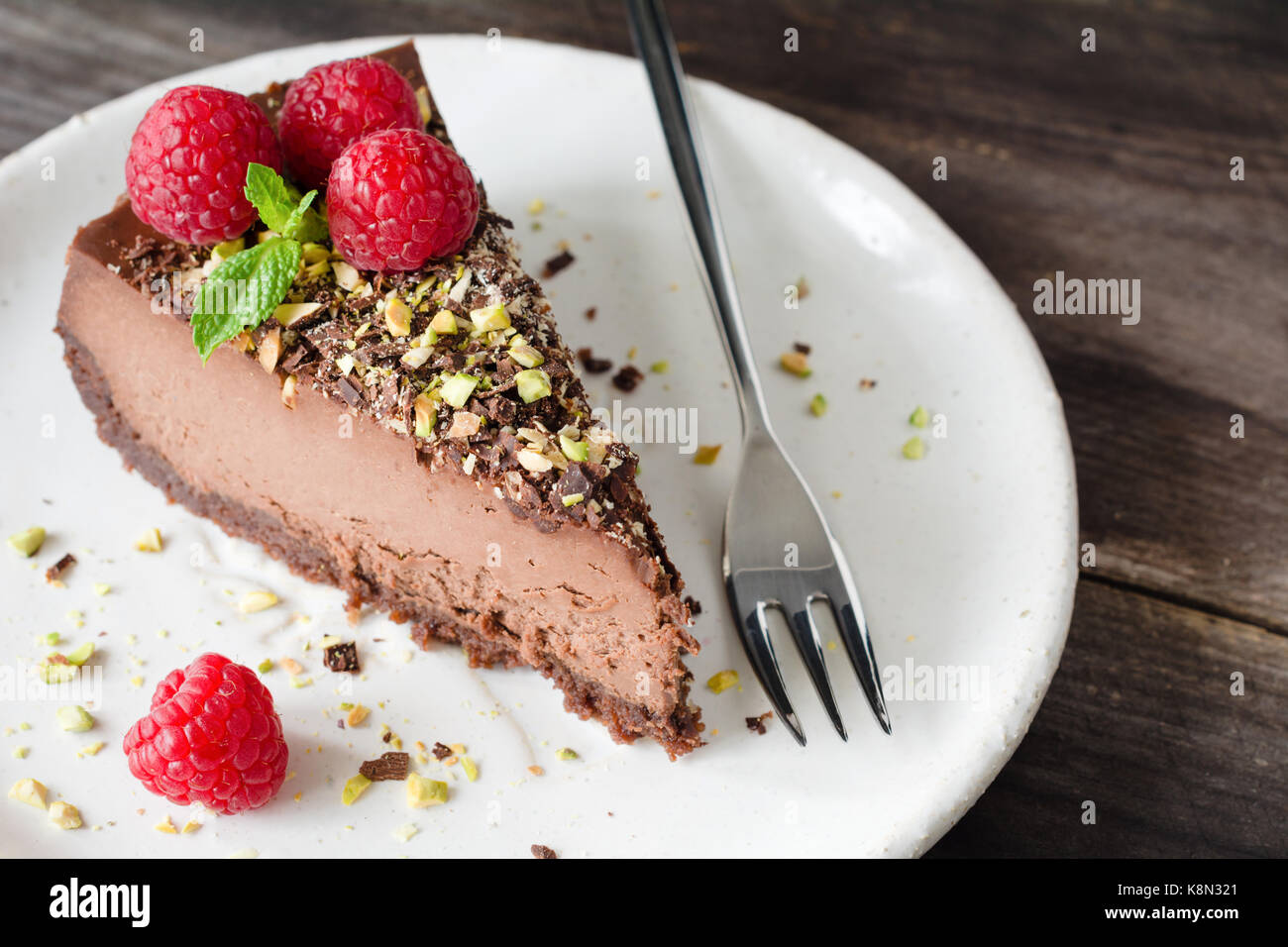 Slice of chocolate cheesecake decorated with pistachios, raspberries ...