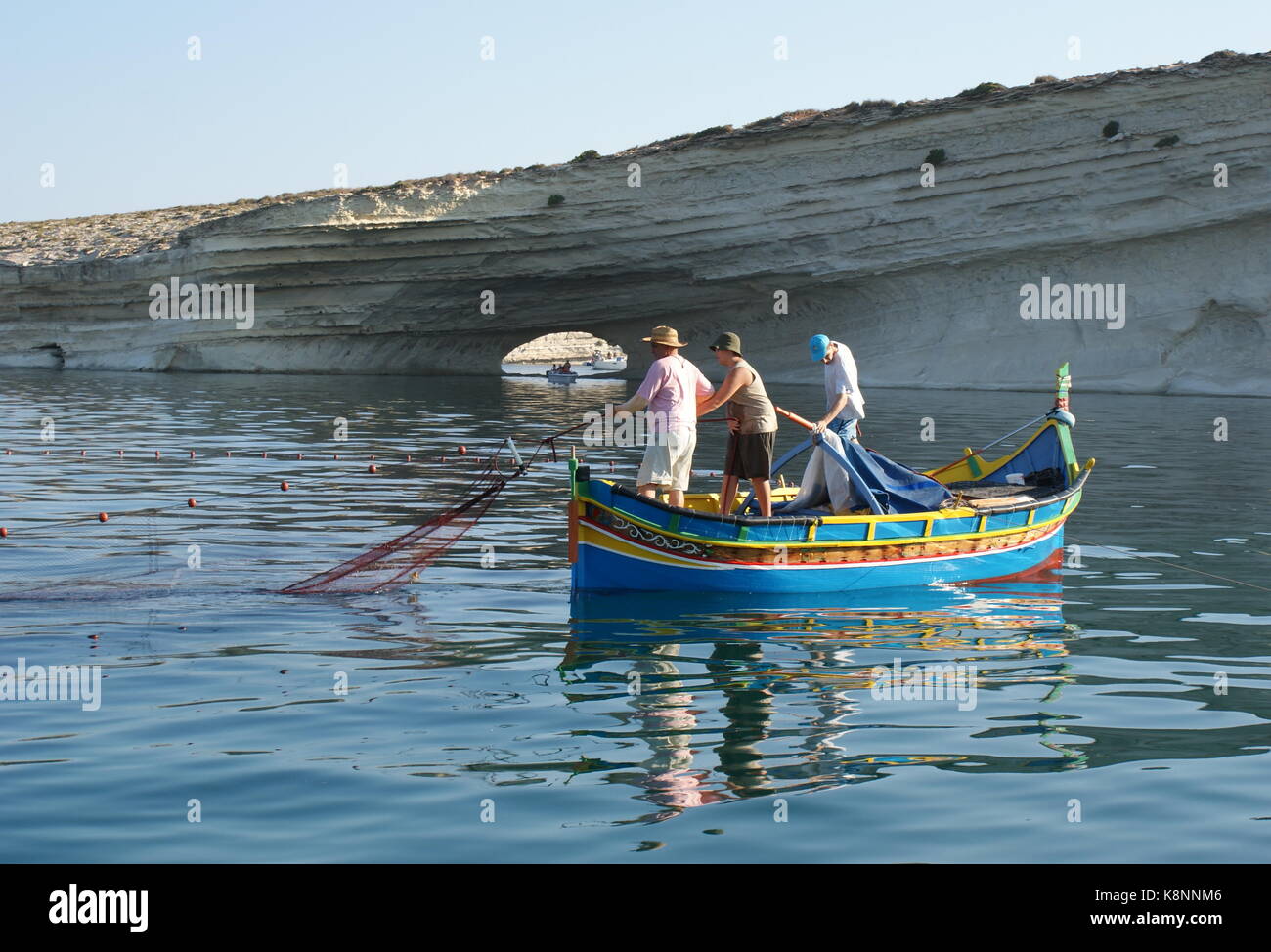 Fishing from a traditional colourful luzzu boat, Il-Hofra I-Kbira bay ...