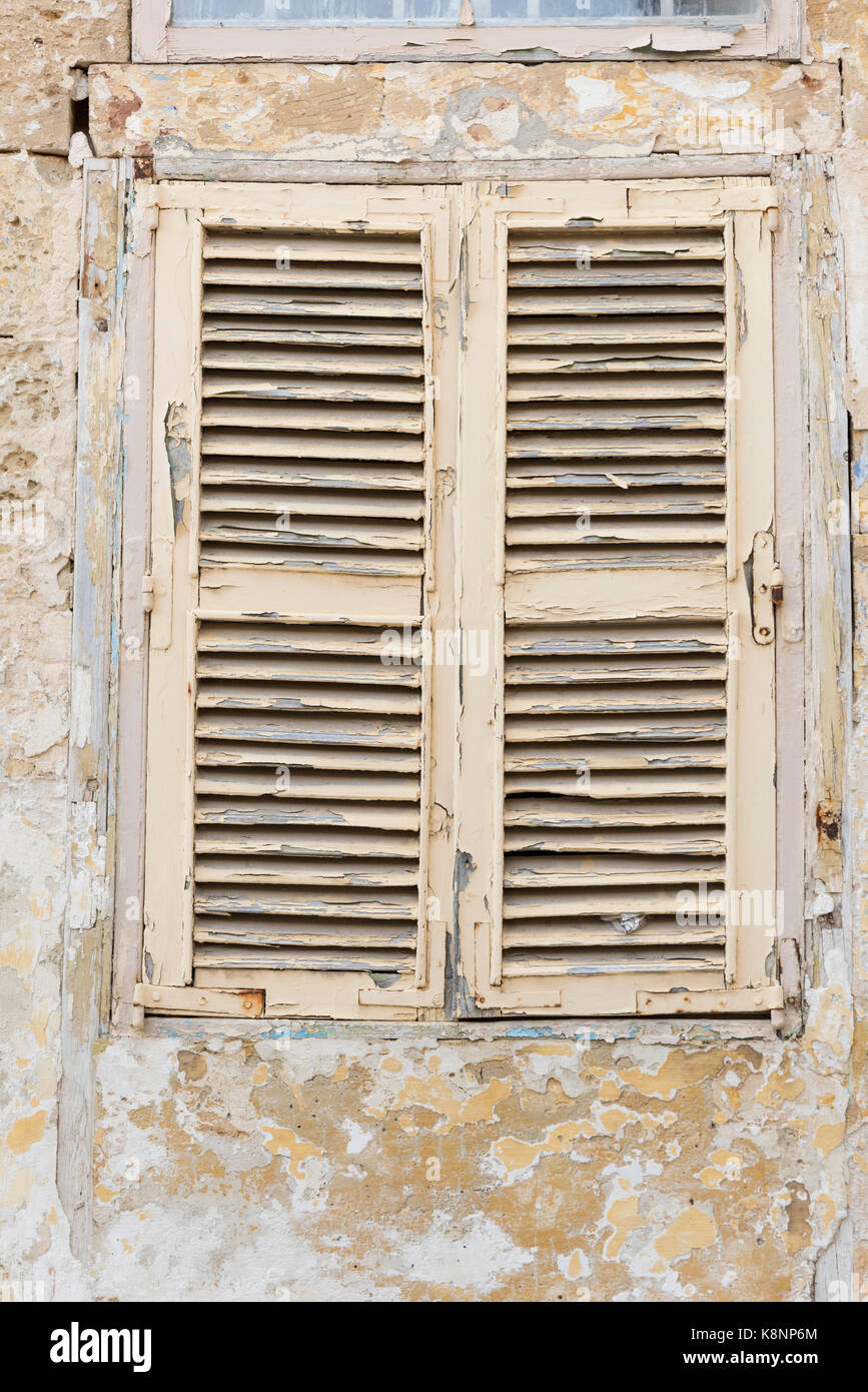 An old shuttered window on a building in Malta with peeling paint and ...