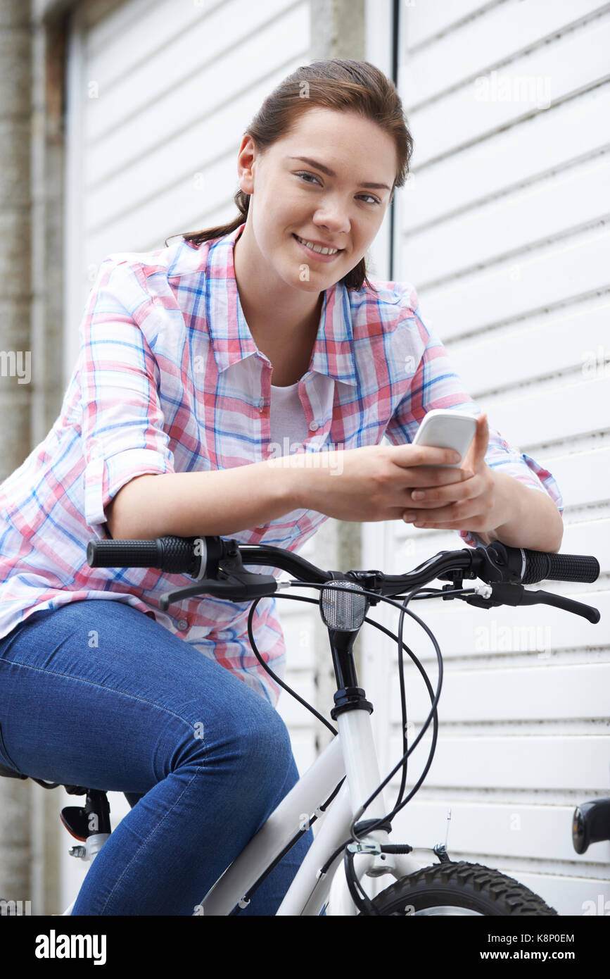 Teenage Girl In Urban Setting Using Mobile Phone Whilst Riding Bike ...
