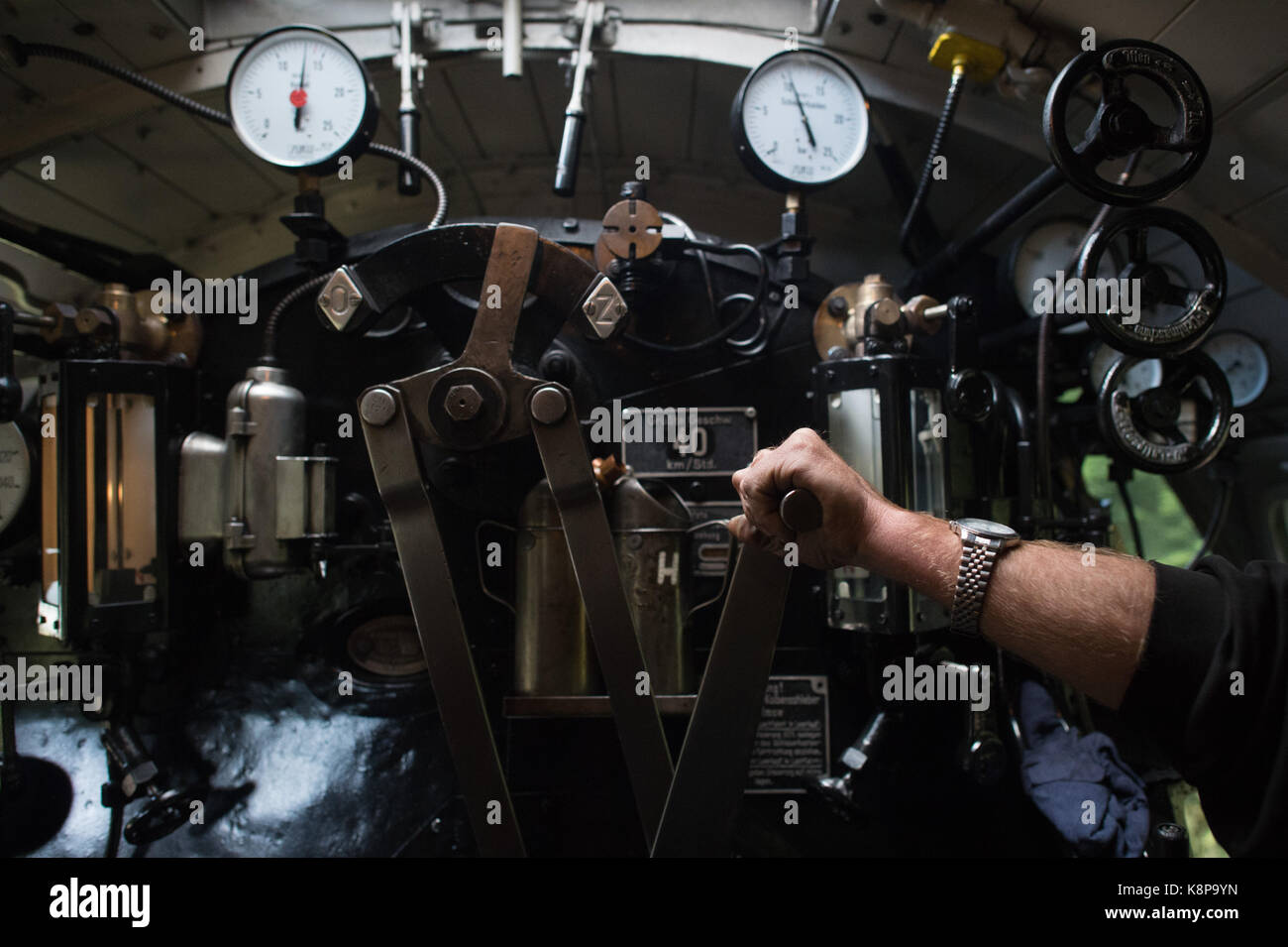 The hand of the train driver can be seen on the controls in the cab of ...