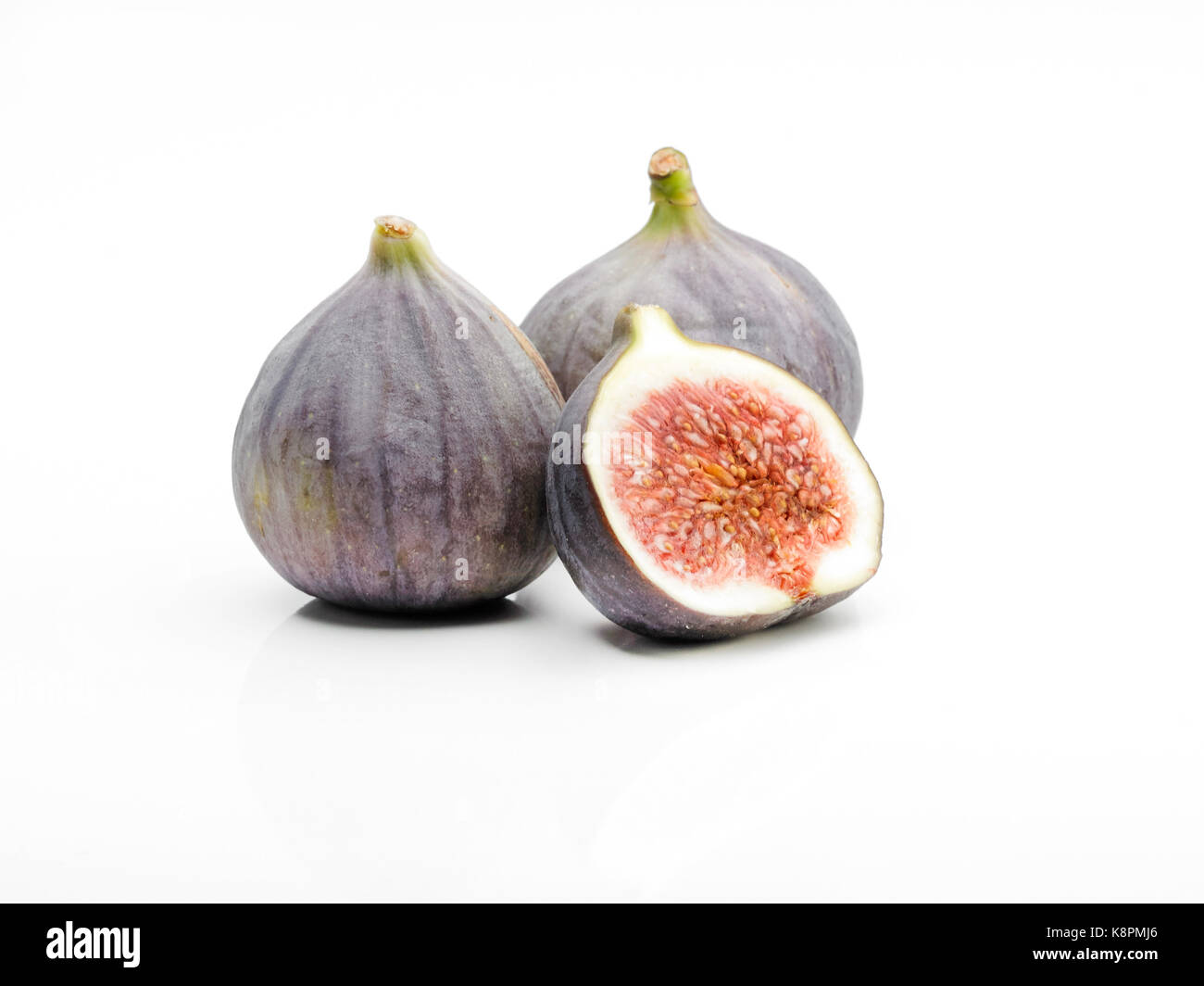 Two whole Figs and a sliced one on a white background Stock Photo - Alamy