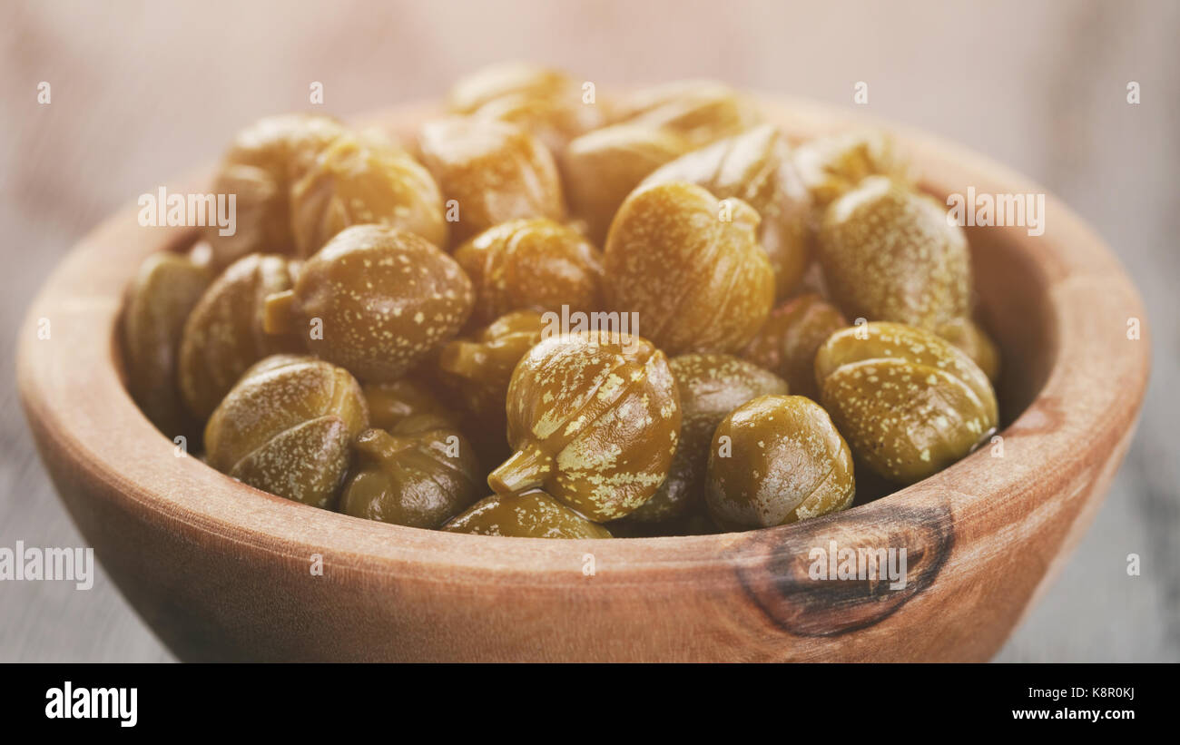 marinated capers in olive bowl on wood table Stock Photo - Alamy