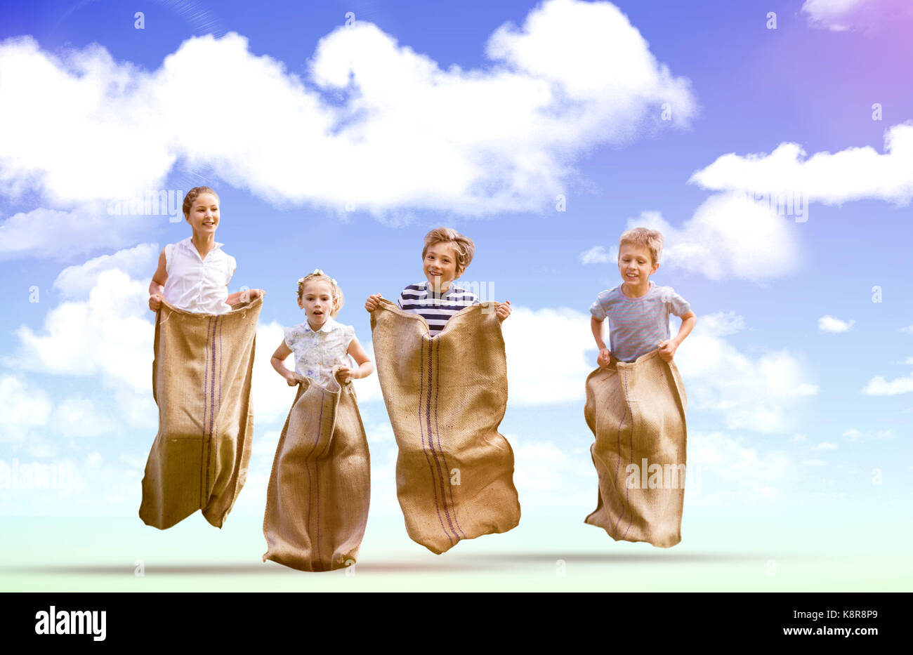 Friends playing sack race against blue sky Stock Photo - Alamy
