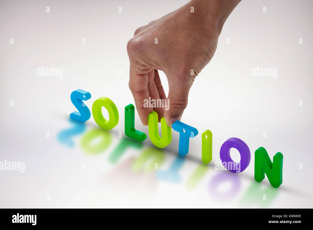 Cropped hand of businessman arranging solution word against grey ...