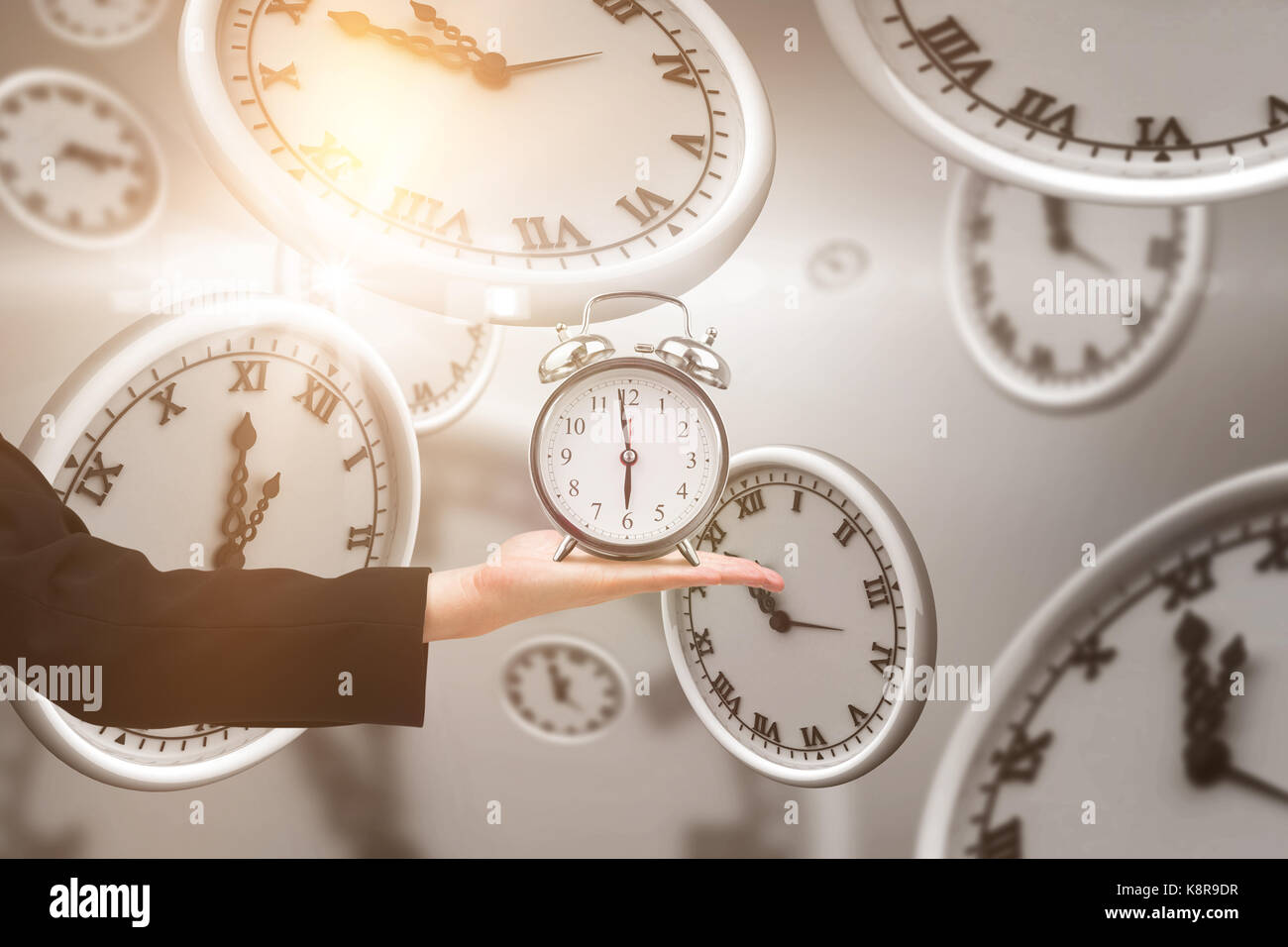 hand holding alarm clock against graphic image of clocks Stock Photo ...