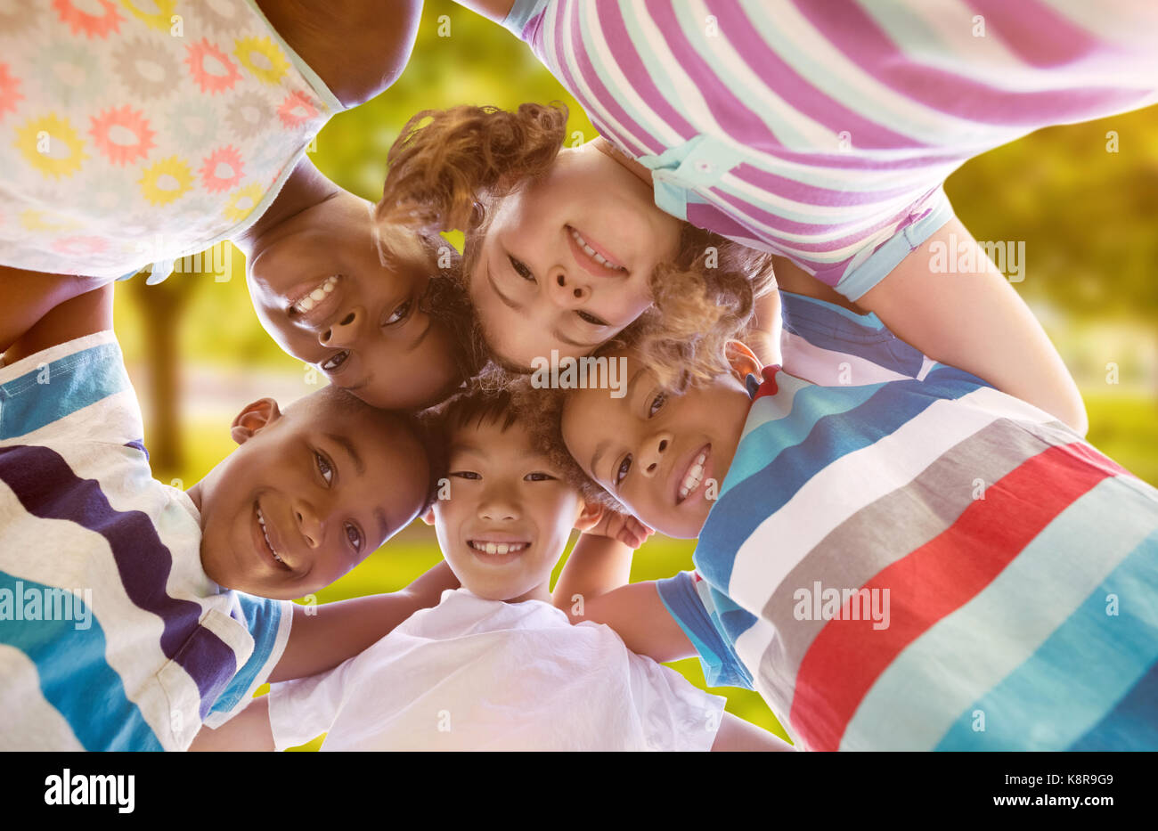 Friends forming huddle against trees in grassy landscape Stock Photo ...