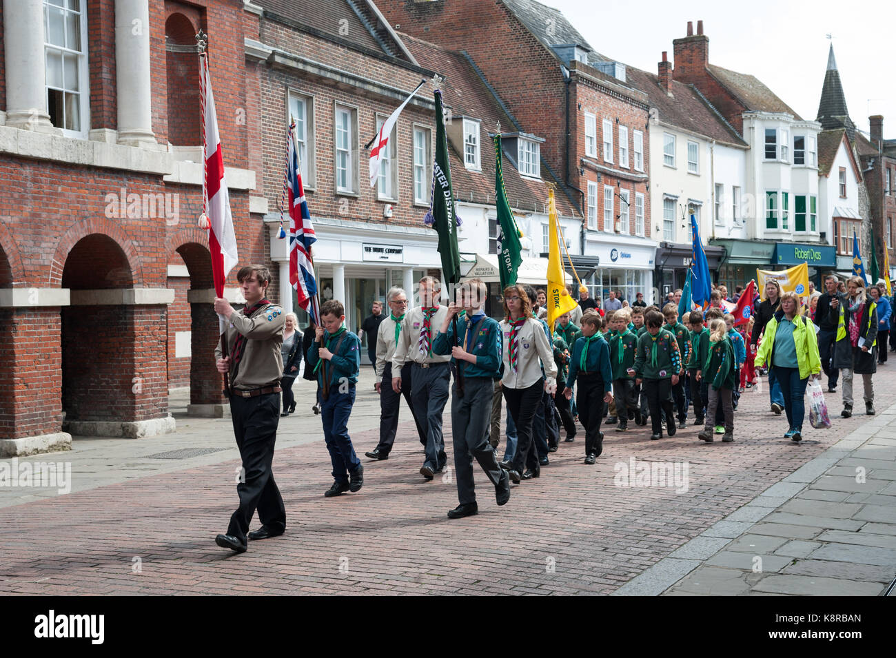 A group of scouts holding flags parade along North Street in the city ...