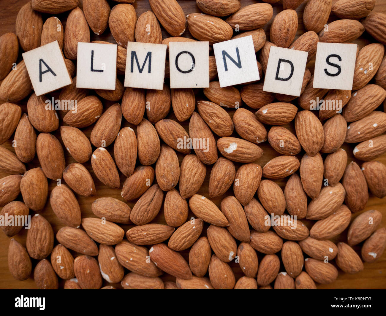 A pile of almond nuts with the word "Almonds" spelled out woth wooden ...