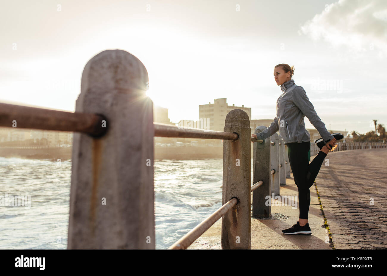 Woman runner doing stretching exercises at seaside promenade. fitness ...