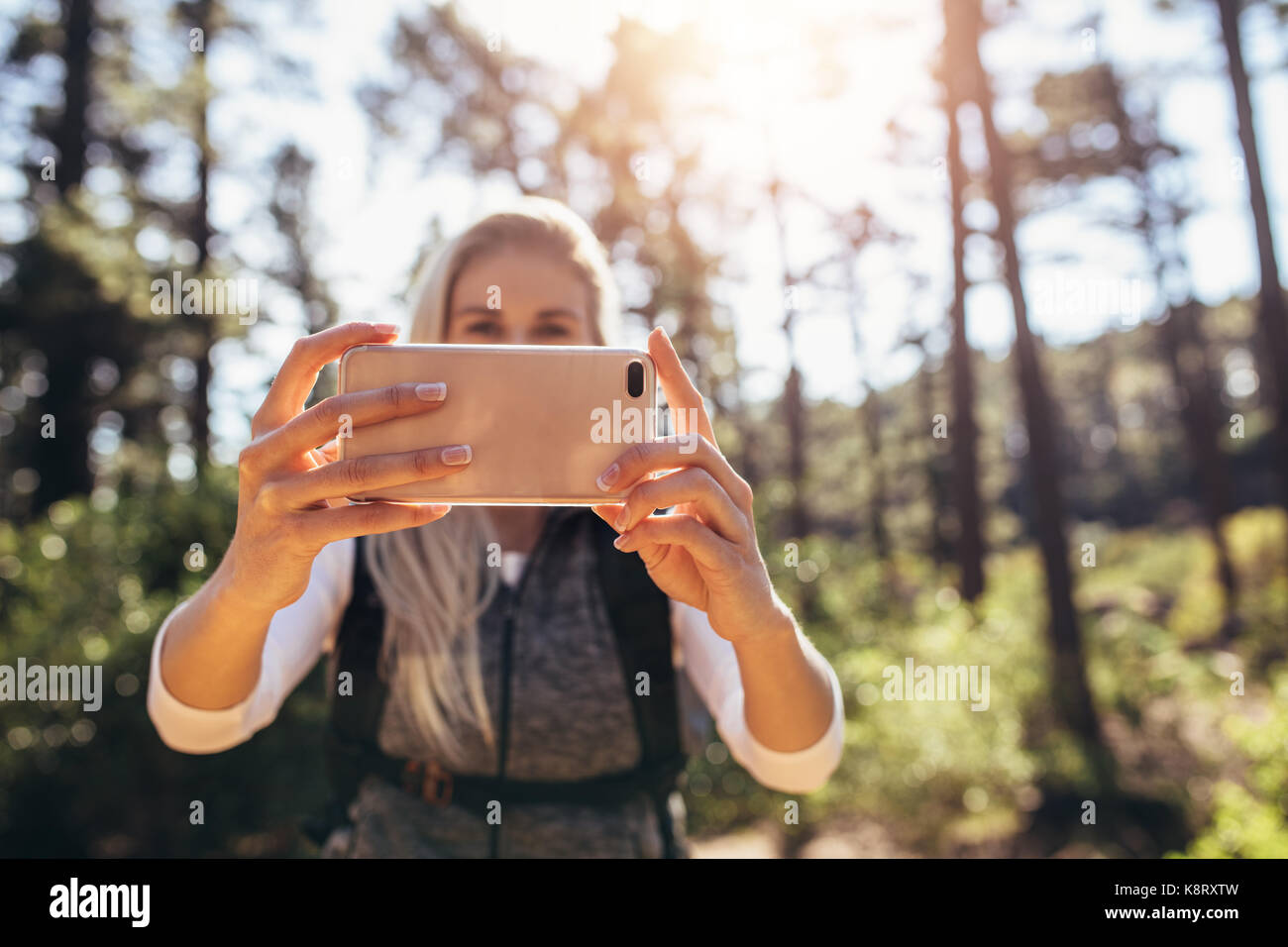 Woman taking photograph using a mobile phone during trekking. Woman ...