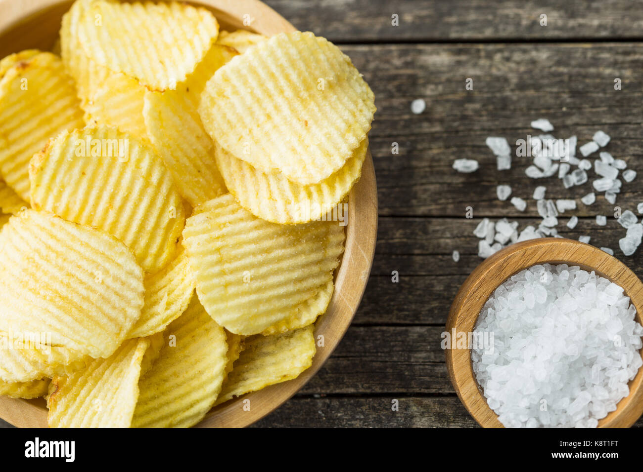 Crispy potato chips and salt in bowl. Salted potato chips. Top view ...